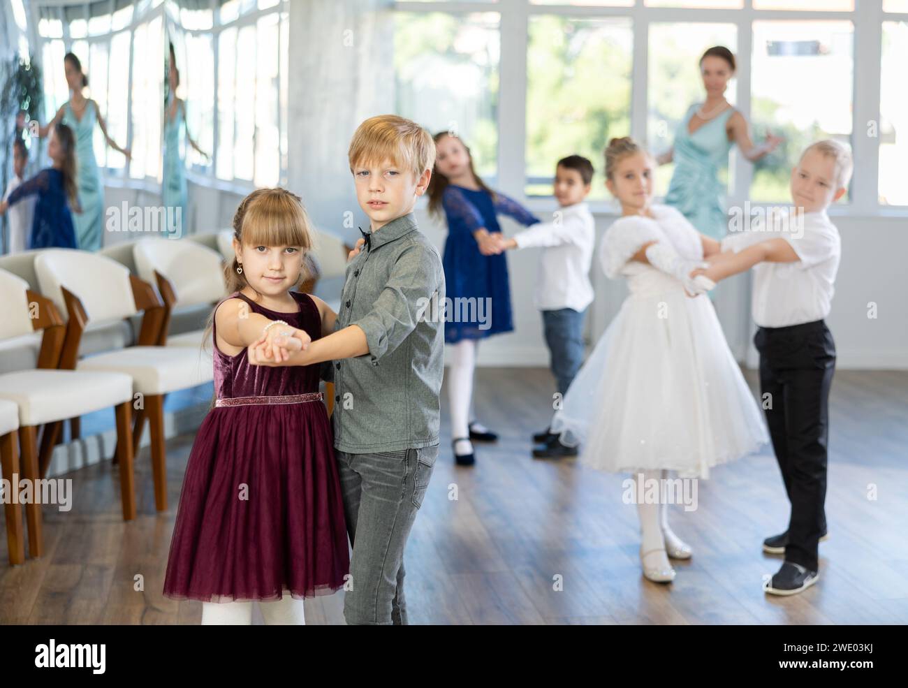 Little children in elegant dresses practicing waltz dance in school ...