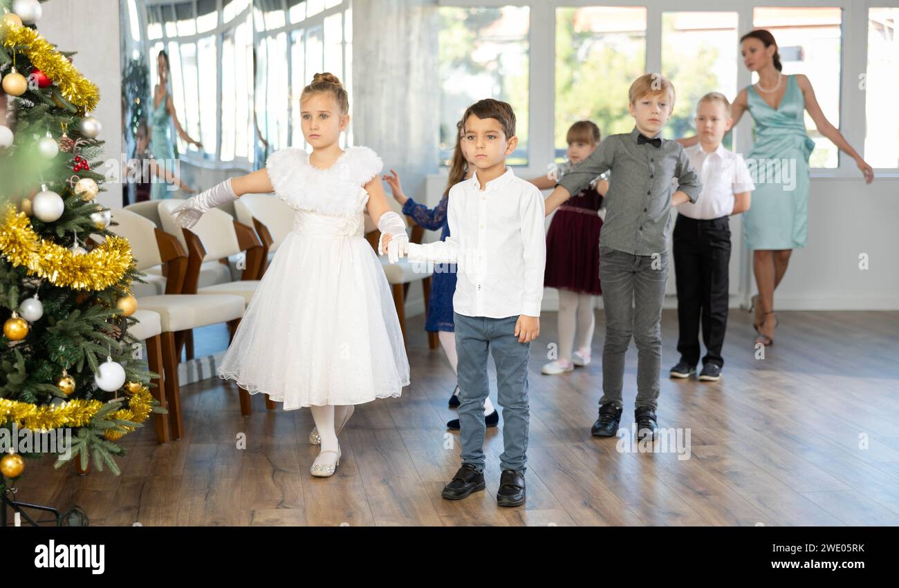 Preteen girls and boys performing curtsy and bow during festive dance ...