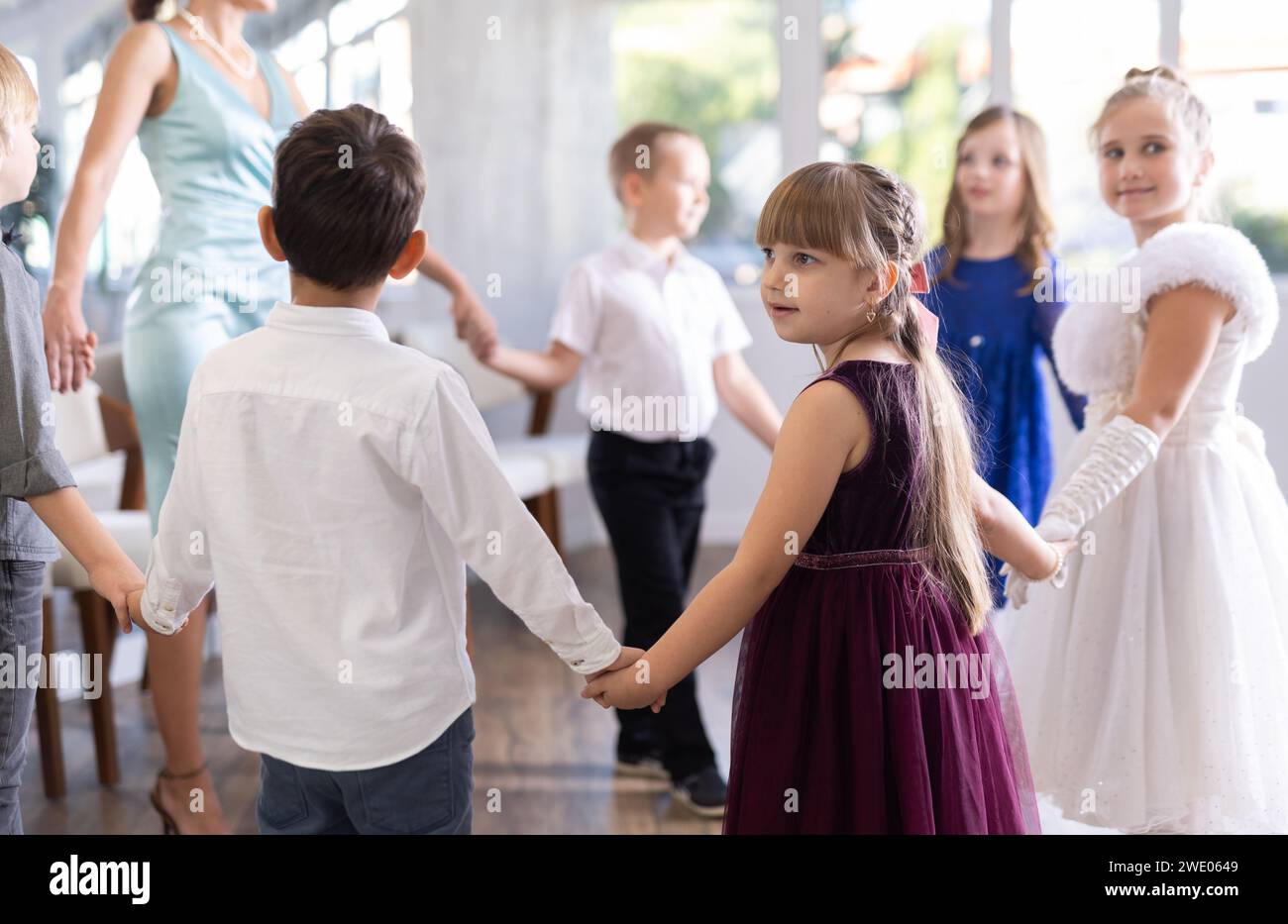 Class of preteen pupils learning circle dance with female teacher Stock ...
