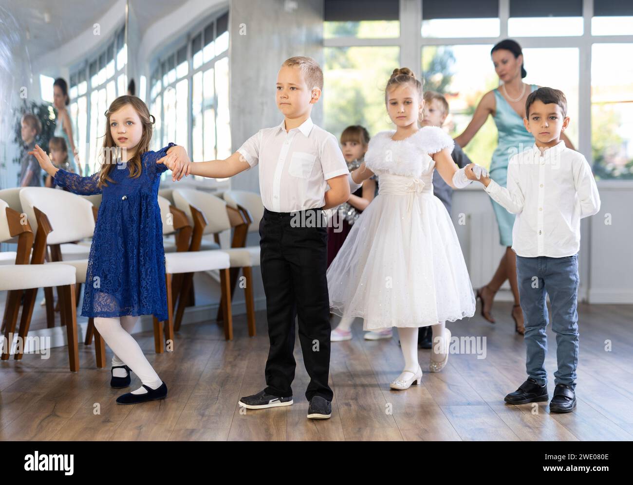 Preteen girls and boys performing curtsy and bow during festive dance ...