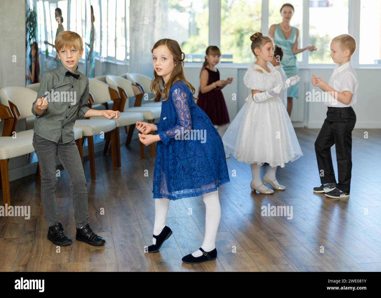 Interested preteen pupils rehearsing twist dance steps in classroom ...