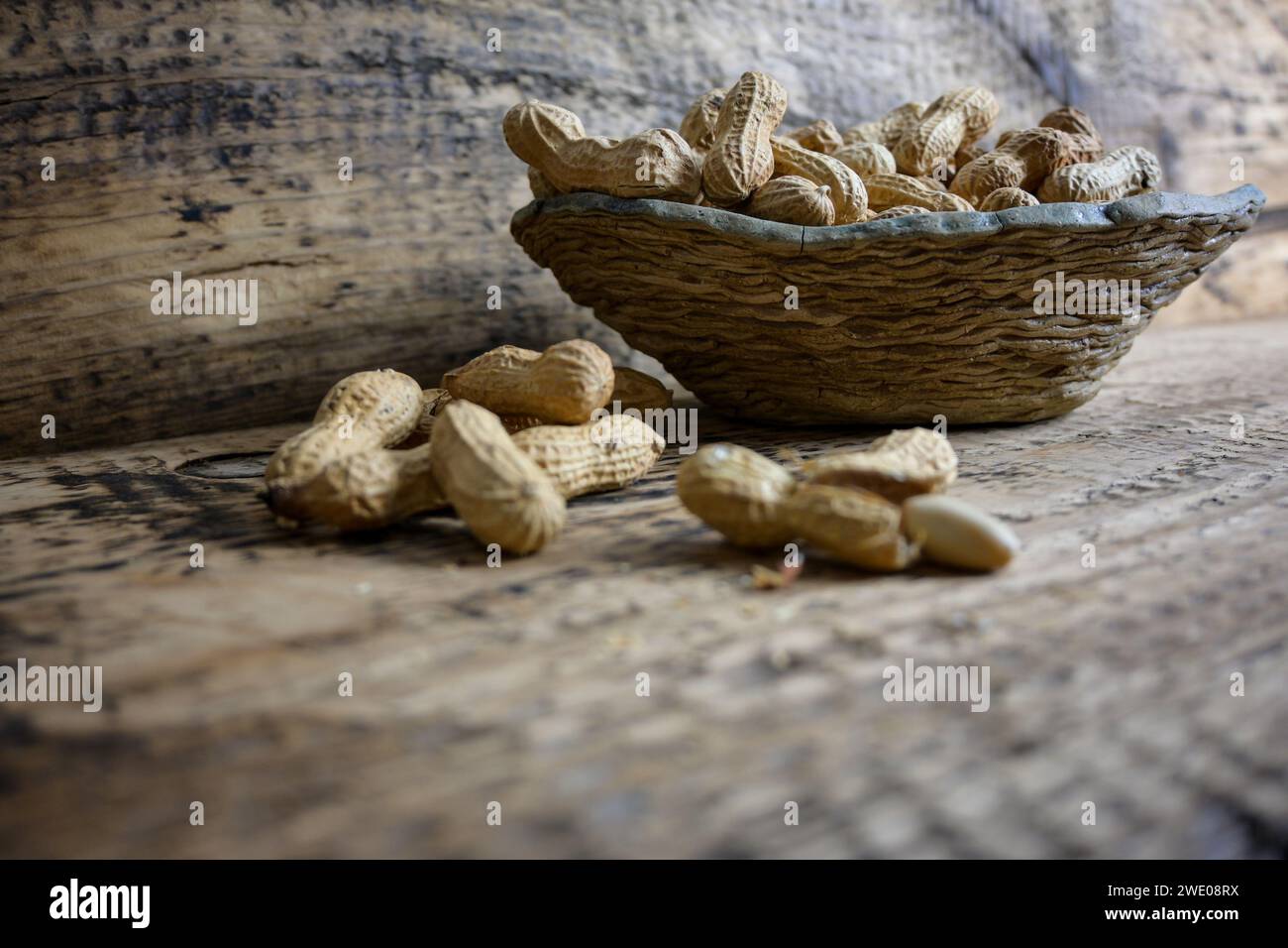 walnuts scattered on a wooden background and a side view of a bowl full ...