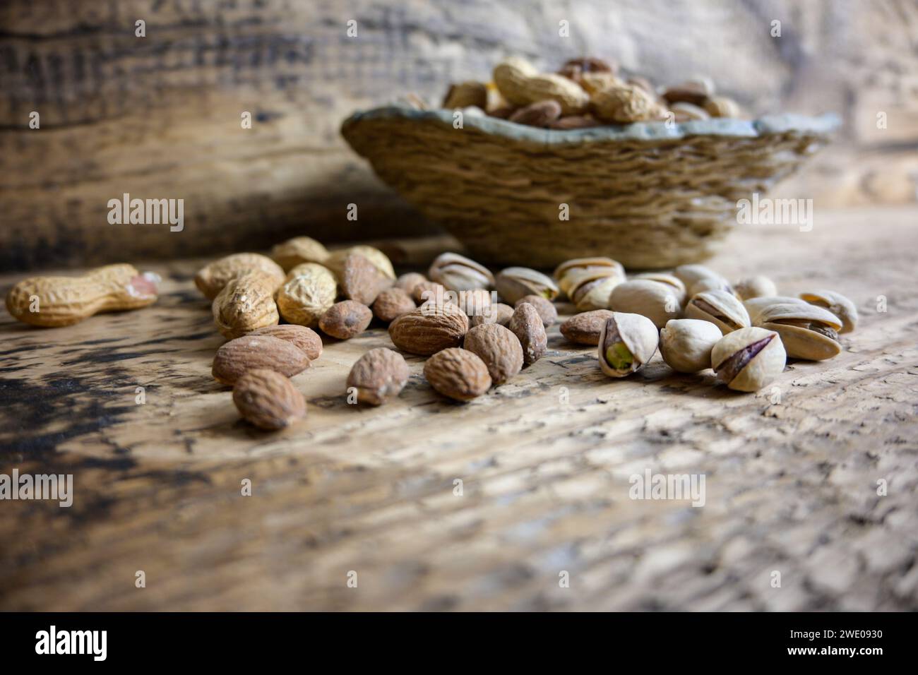 scattered nuts on wooden background, side view of bowl full of nuts ...