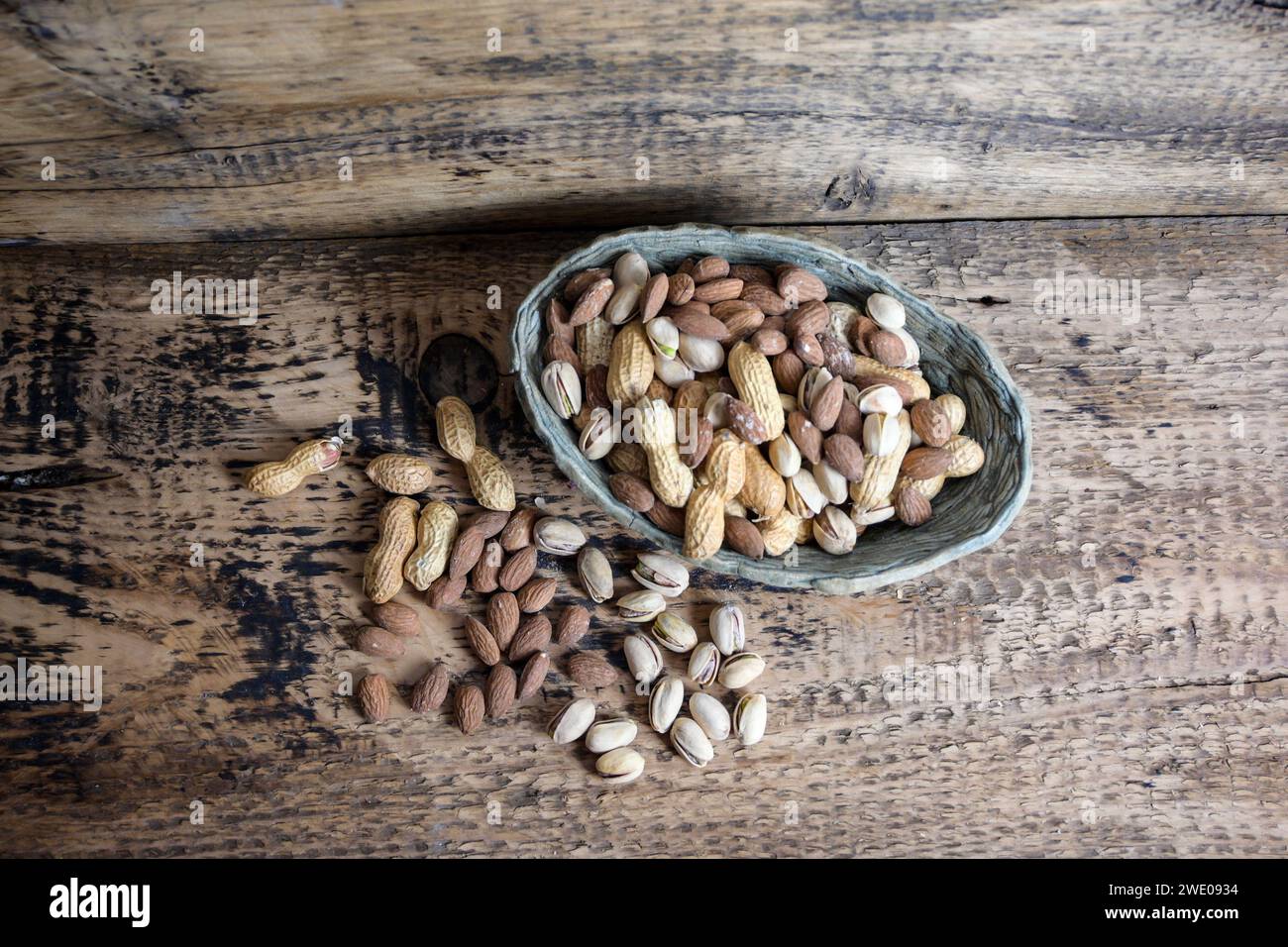 a bowl full of various nuts, top view of the bowl and scattered nuts ...