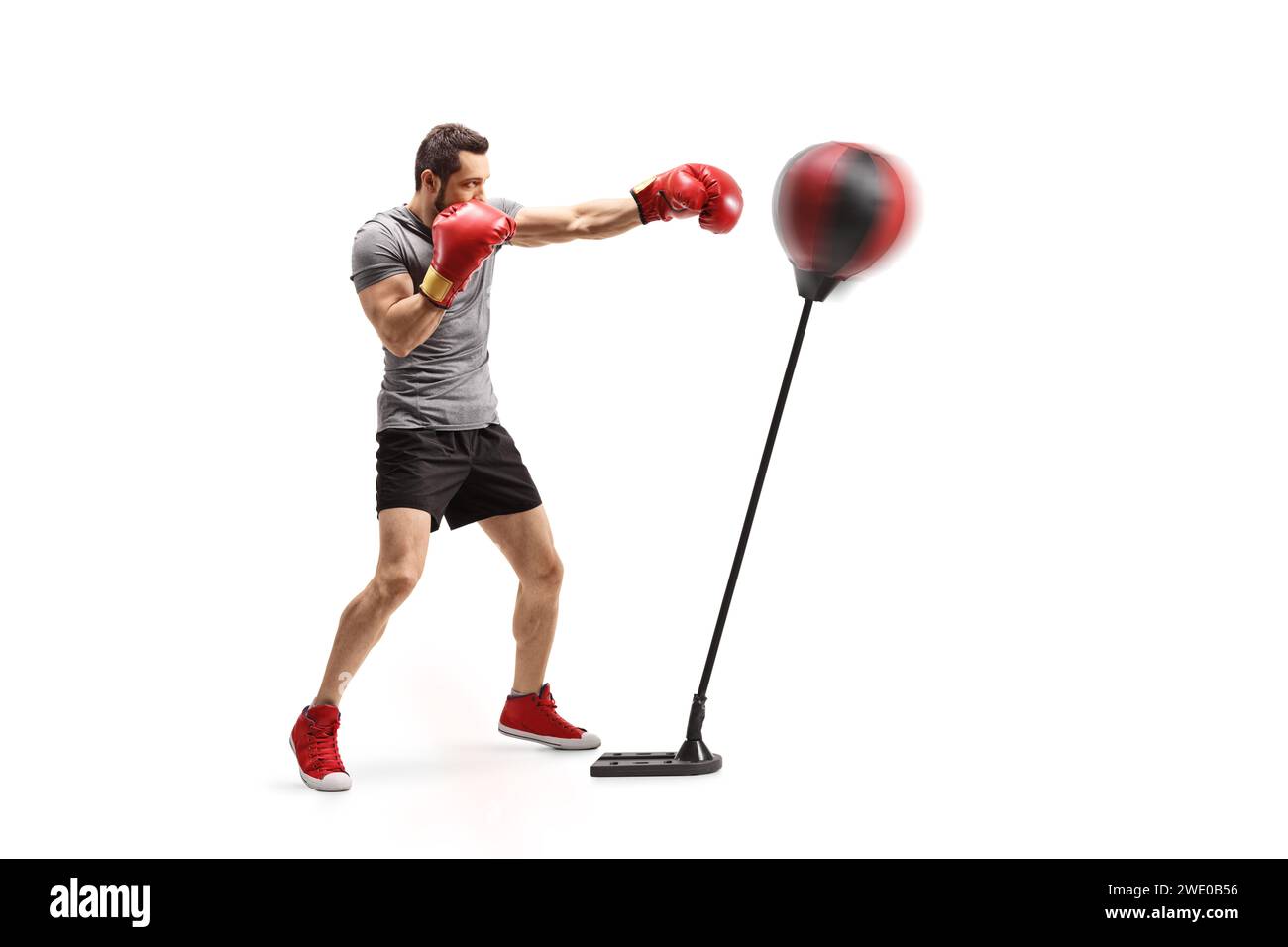 Full length shot of a strong young man punching a stand with boxing ...