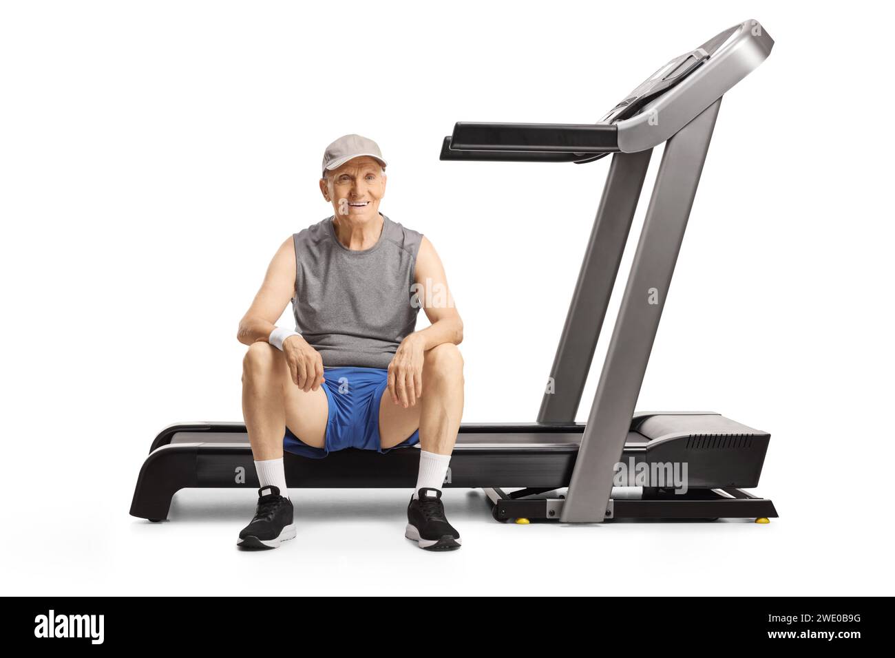 Elderly man resting seated on a treadmill isolated on white background ...
