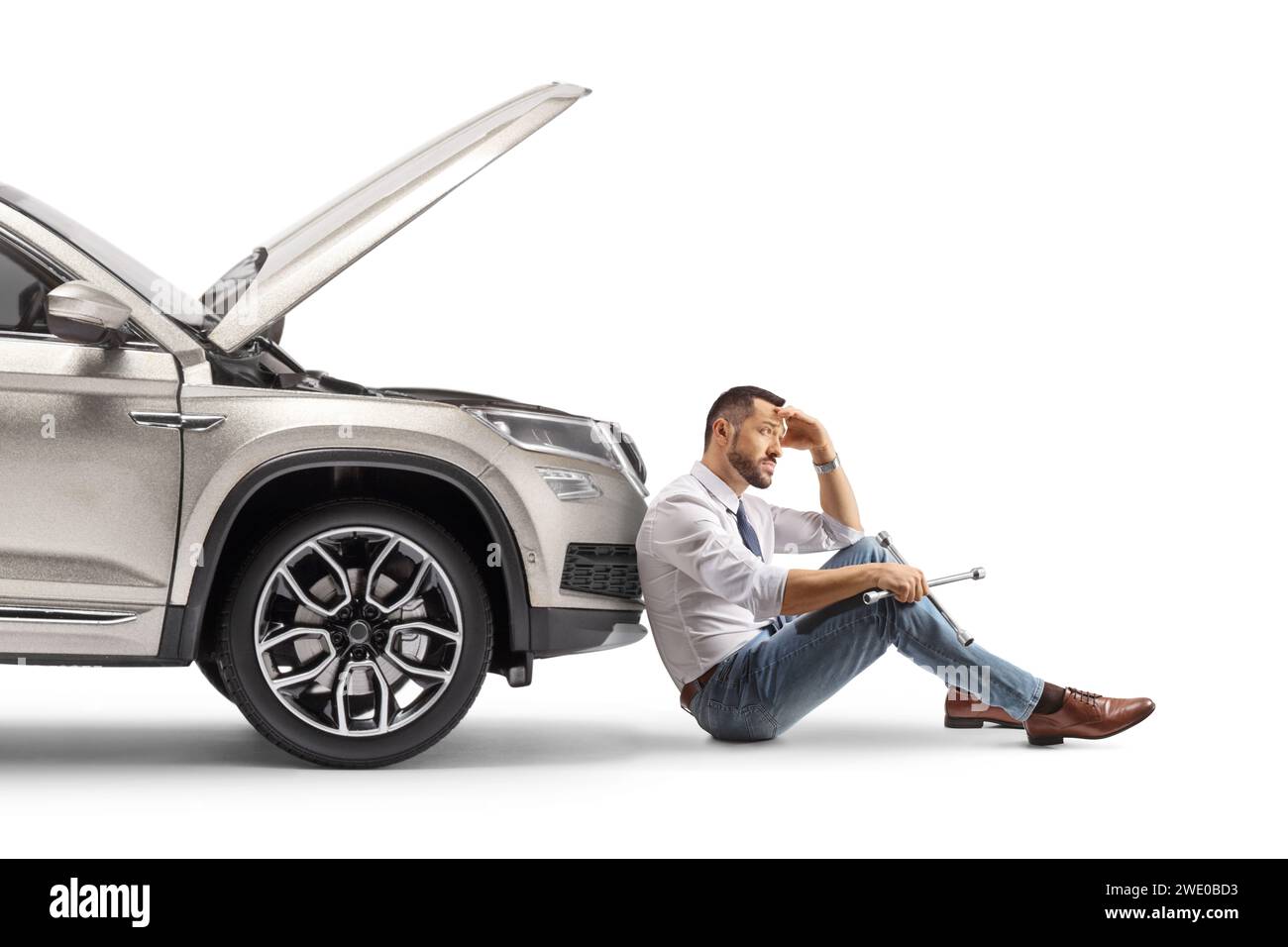 Unhappy driver sitting on the ground in front of a SUV with open hood ...