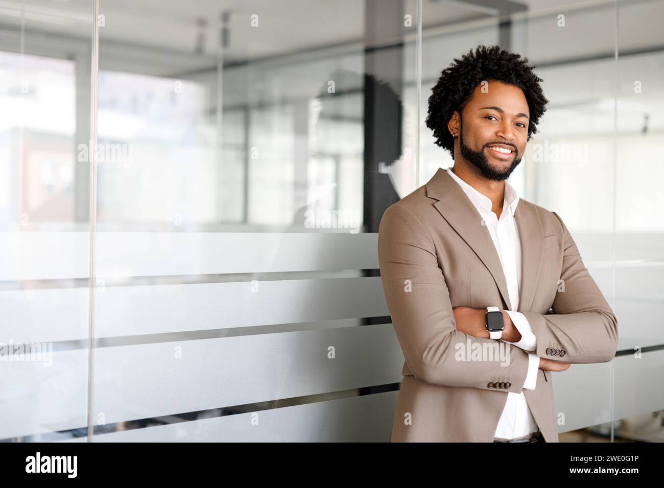 An African-American businessman stands confidently in a modern office ...