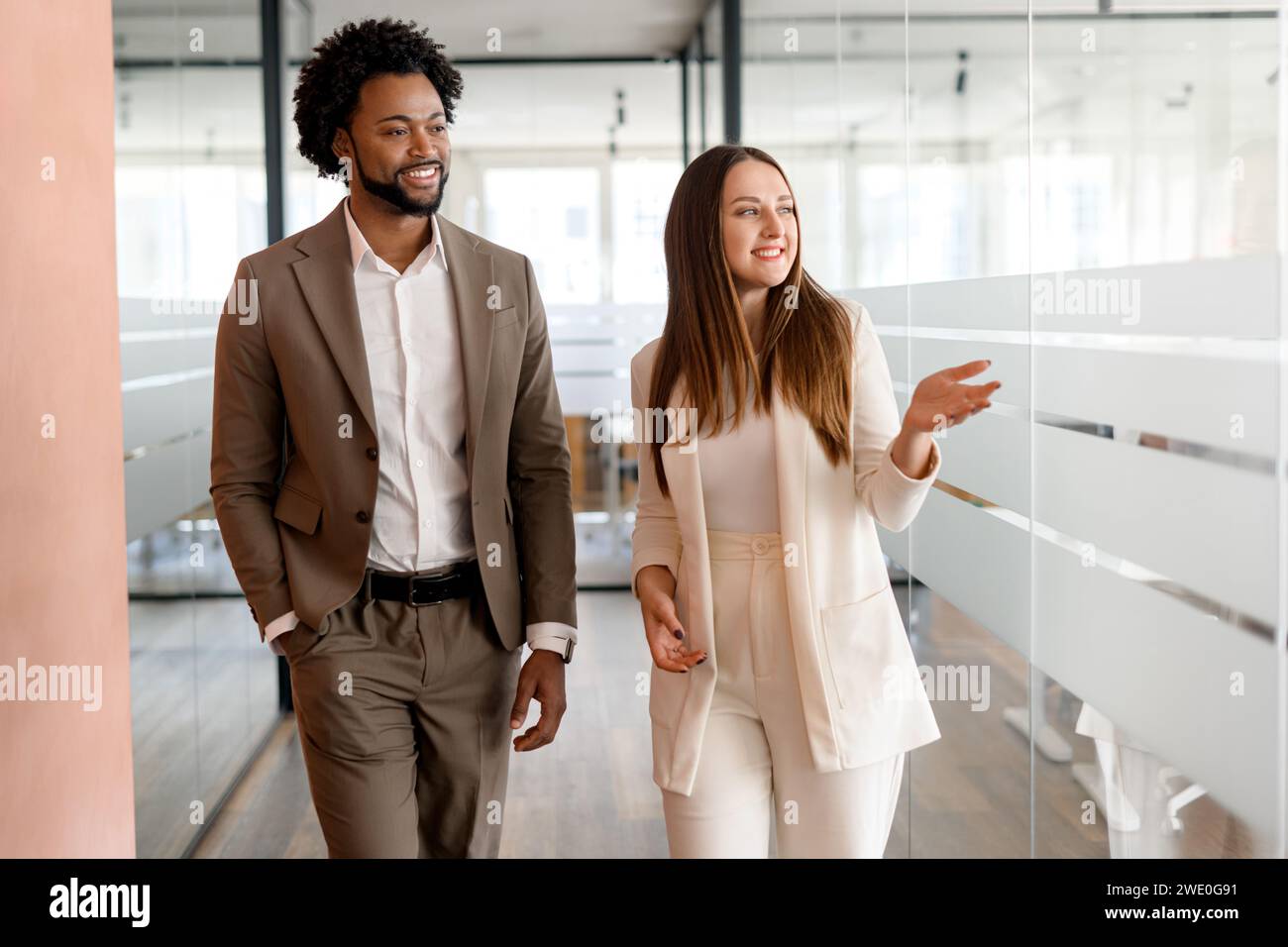 An businessman and female colleague are captured mid-conversation ...