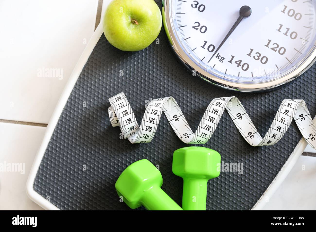 Part of a weight scale with measuring tape, green dumbbells and an ...