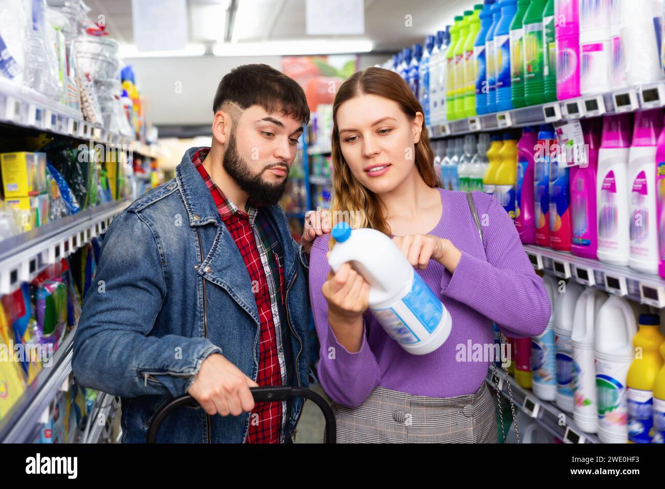 Portrait of positive young woman and man choosing liquid laundry ...