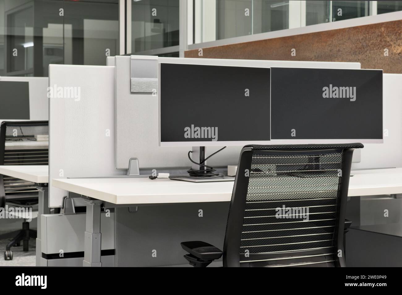 Empty office desk space with computer monitors, desk and chair at a ...