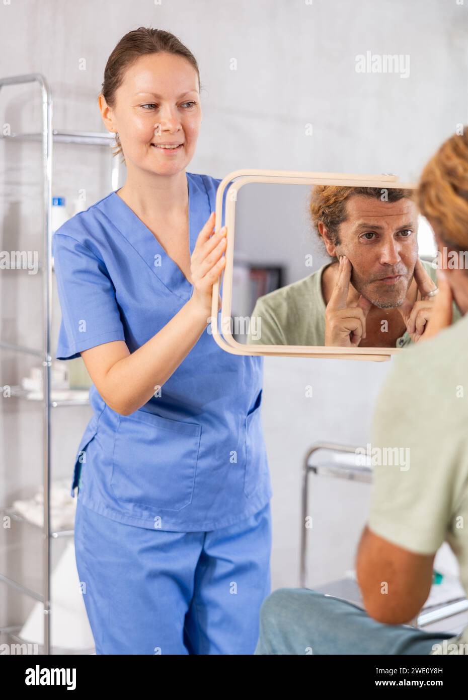 Man examining face after plastic surgery in mirror held by female ...