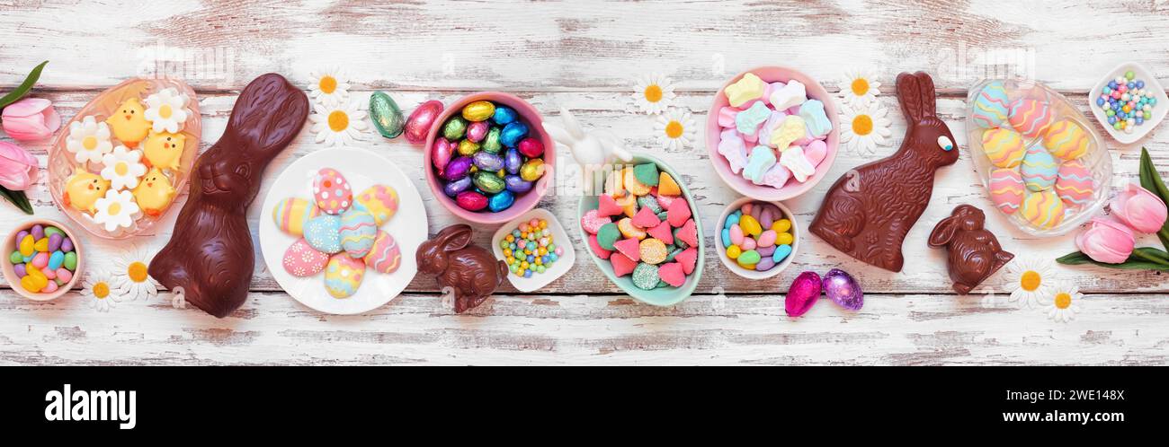 Easter candy table scene. Above view over a white wood banner ...