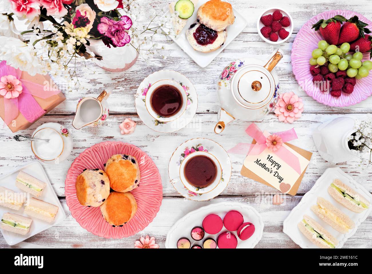 Mother's Day tea table scene over a white wood background. Greeting ...