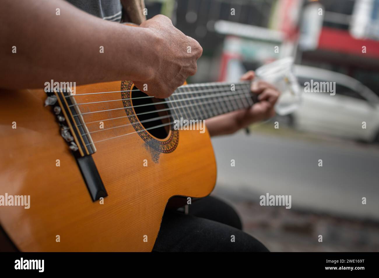 An elderly blind street musician is singing and playing his guitar ...