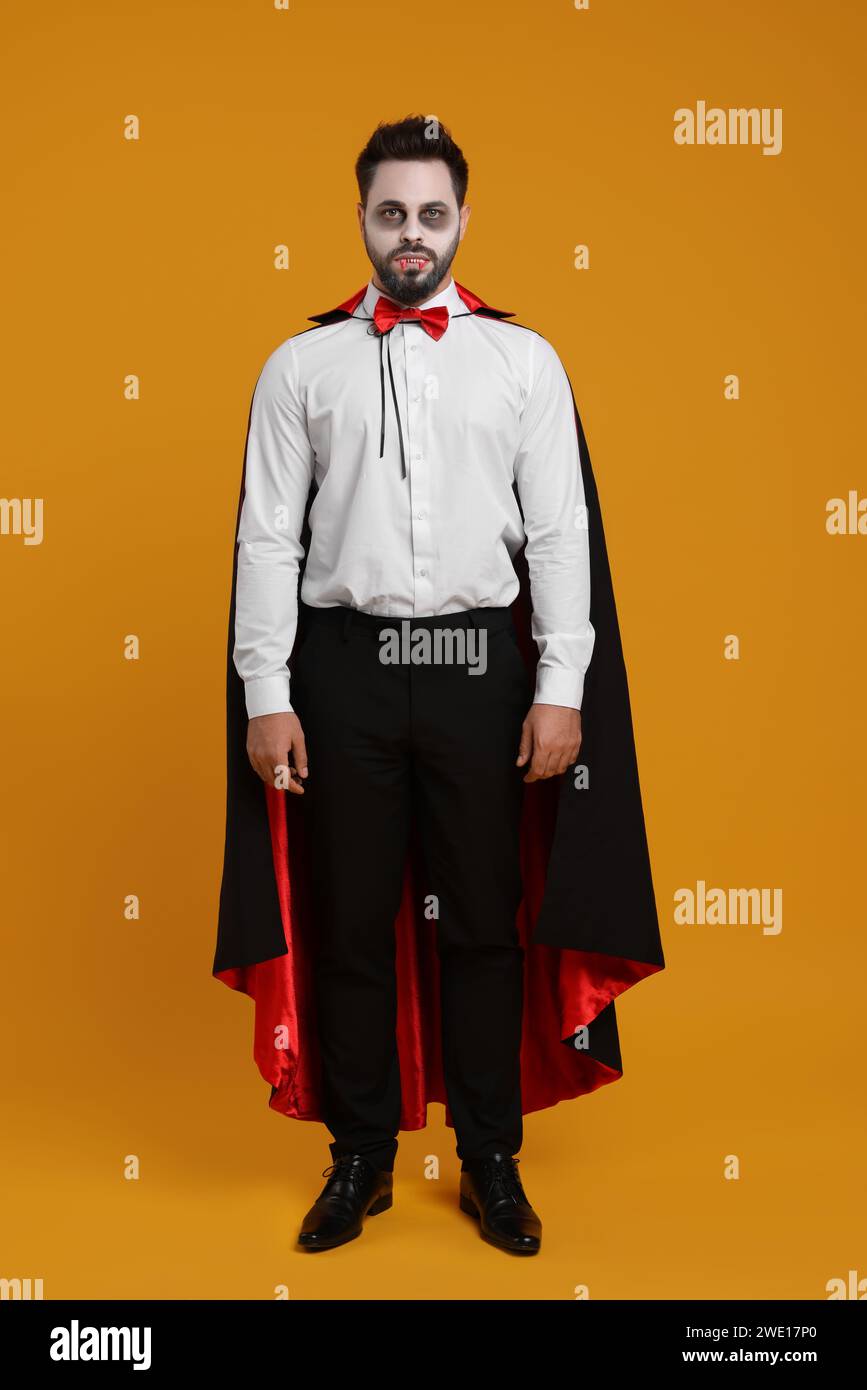 Man in scary vampire costume with fangs on orange background. Halloween ...