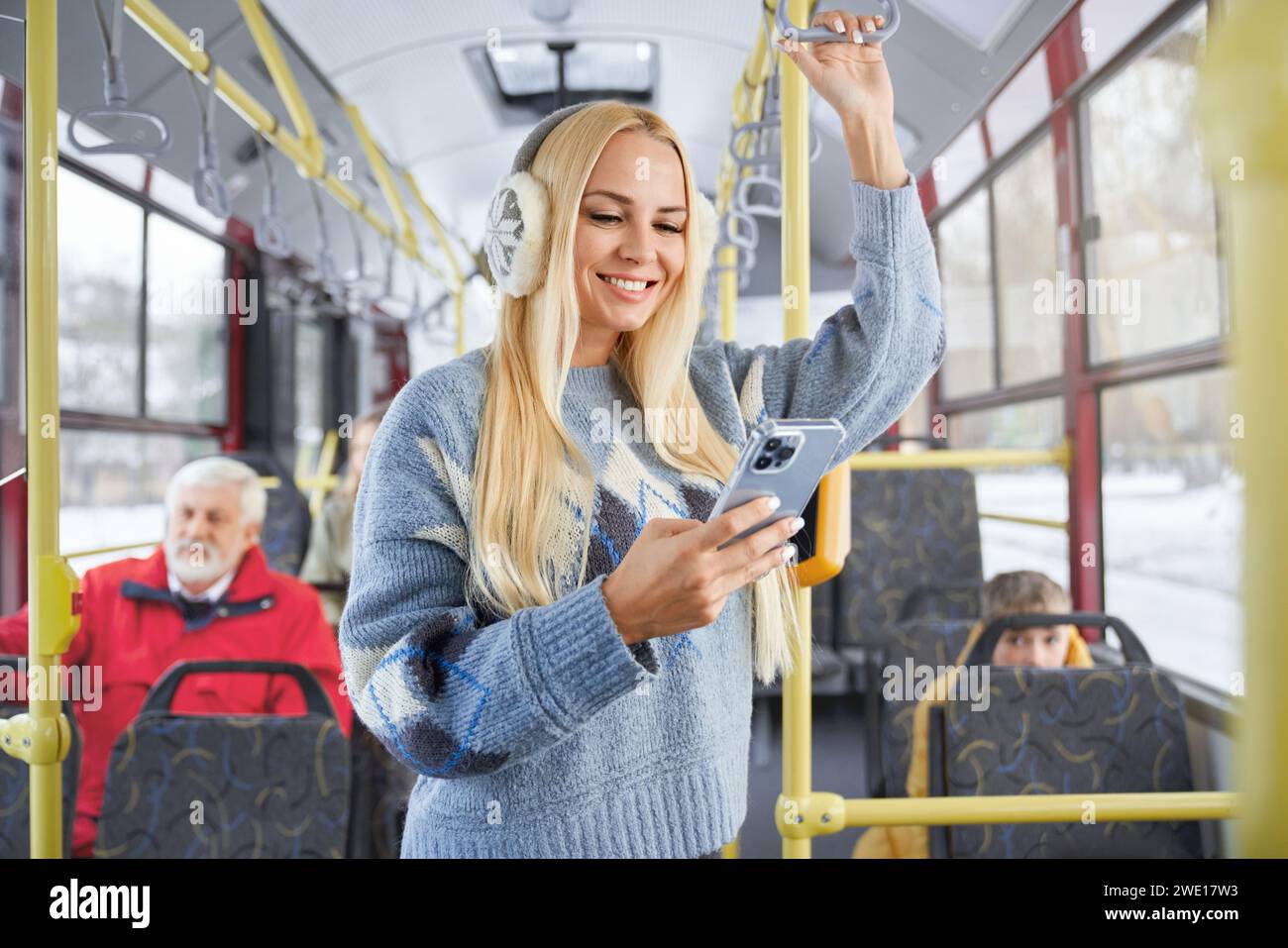 Front view of pritty blonde girl using phone smiling standing inside ...