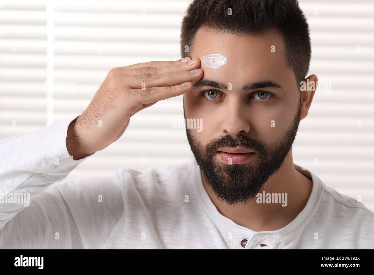 Man with dry skin applying cream onto his forehead indoors Stock Photo ...