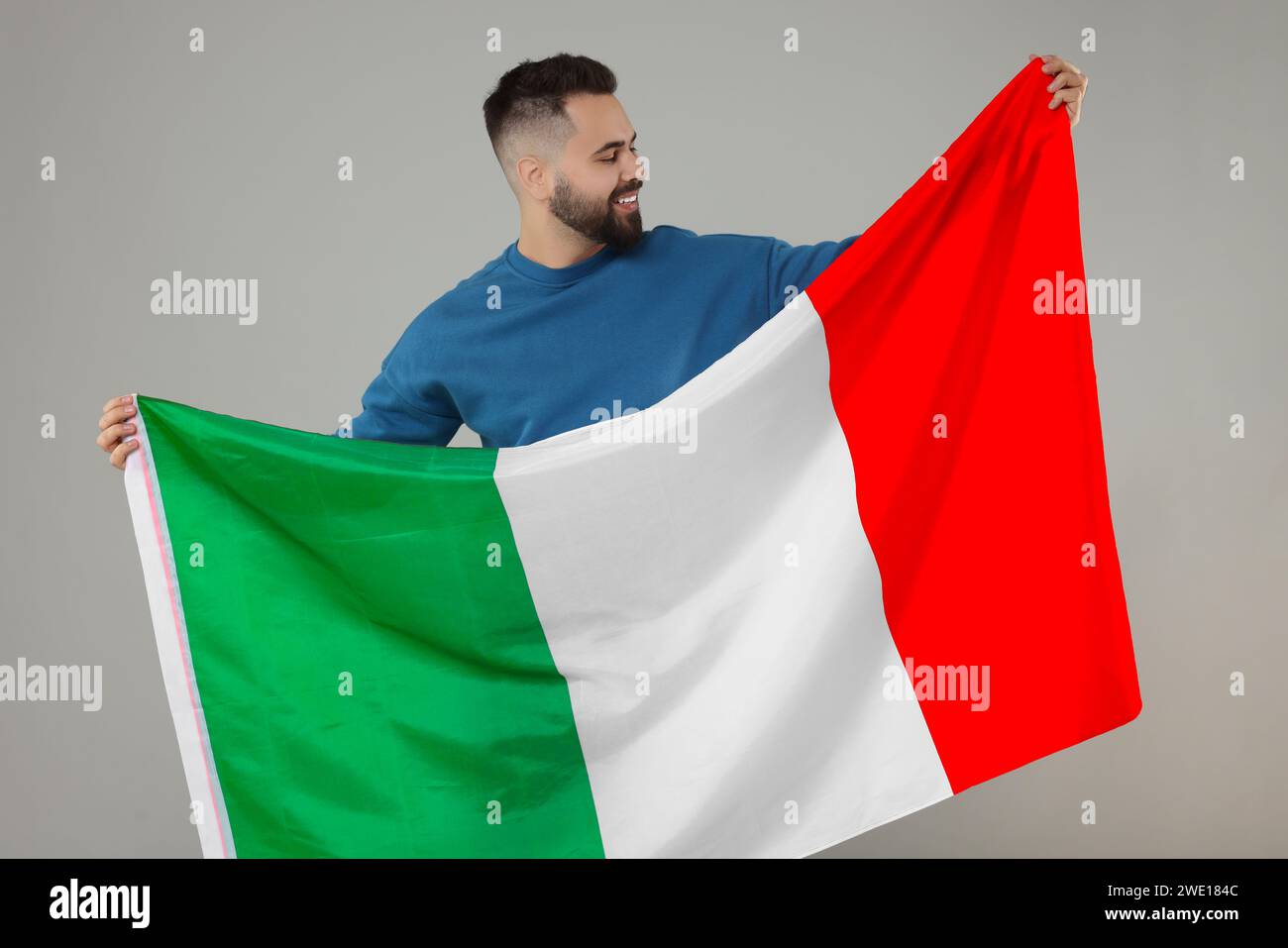 Young man holding flag of Italy on light grey background Stock Photo ...