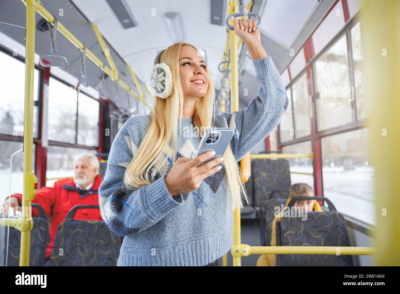 Front view of pretty blonde girl with phone looking at window smiling ...