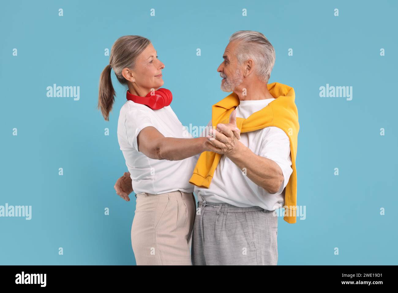 Senior couple dancing together on light blue background Stock Photo - Alamy