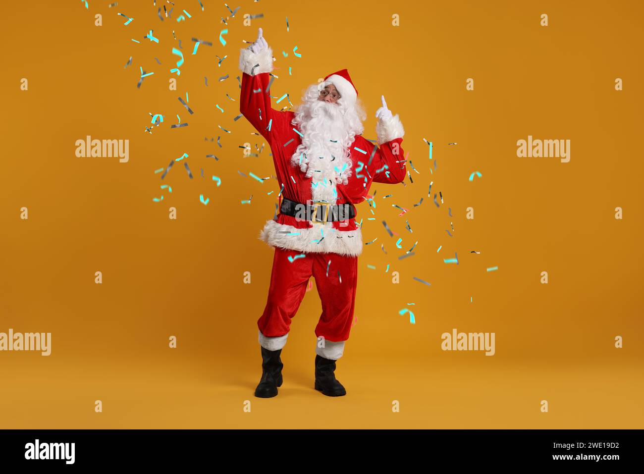 Santa Claus under falling confetti on orange background Stock Photo - Alamy