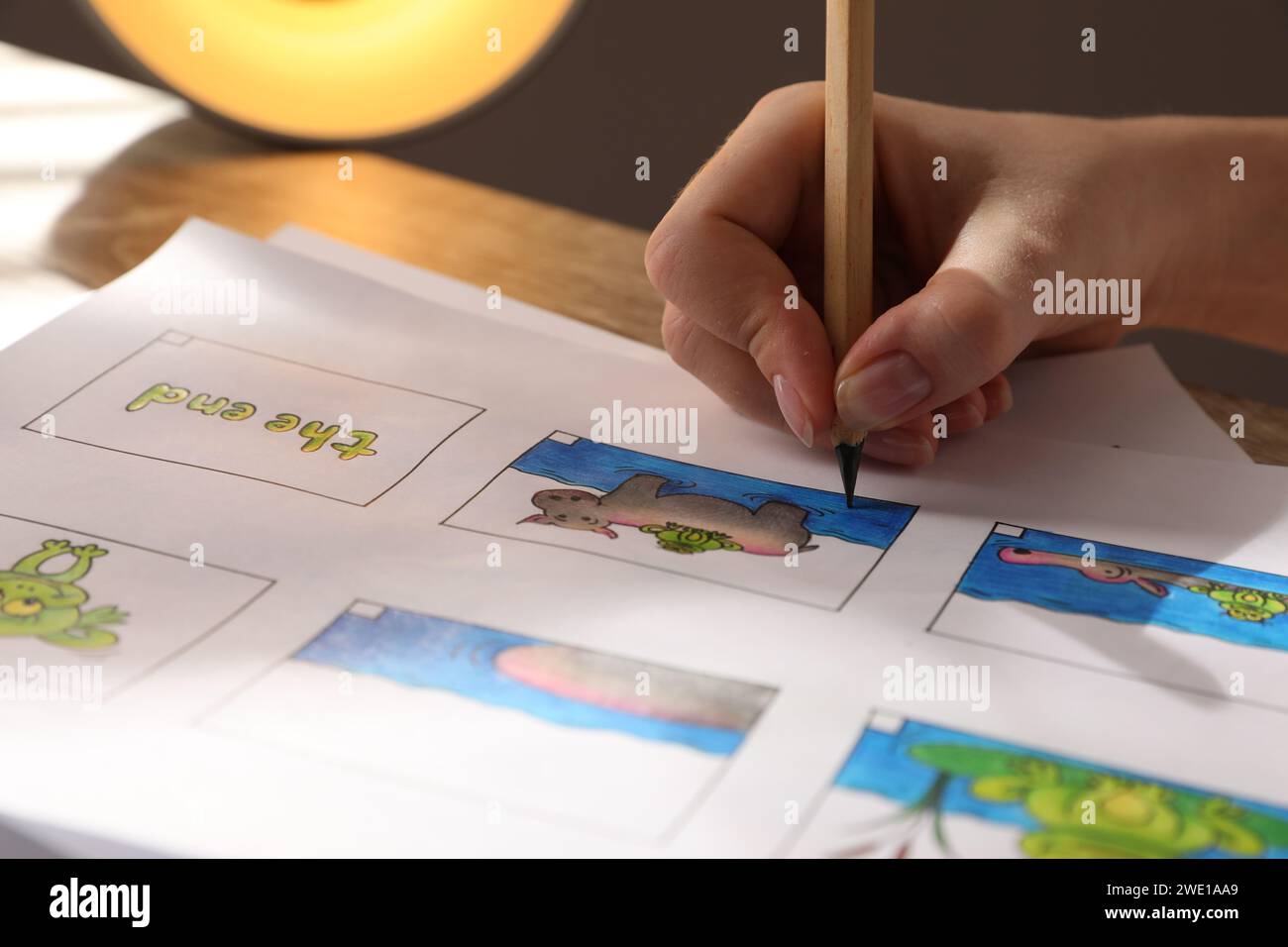 Woman drawing cartoon sketch in storyboard at workplace, closeup. Pre ...