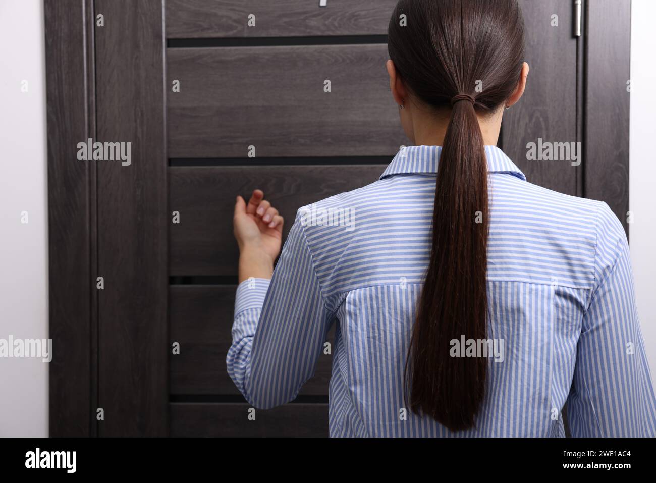 Woman knocking on door indoors, back view. Space for text Stock Photo ...