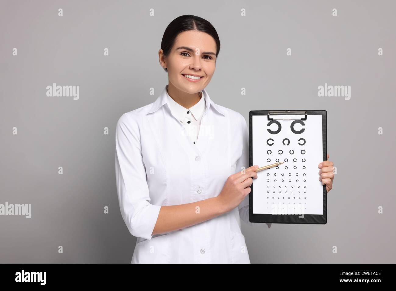 Ophthalmologist pointing at vision test chart on gray background Stock ...