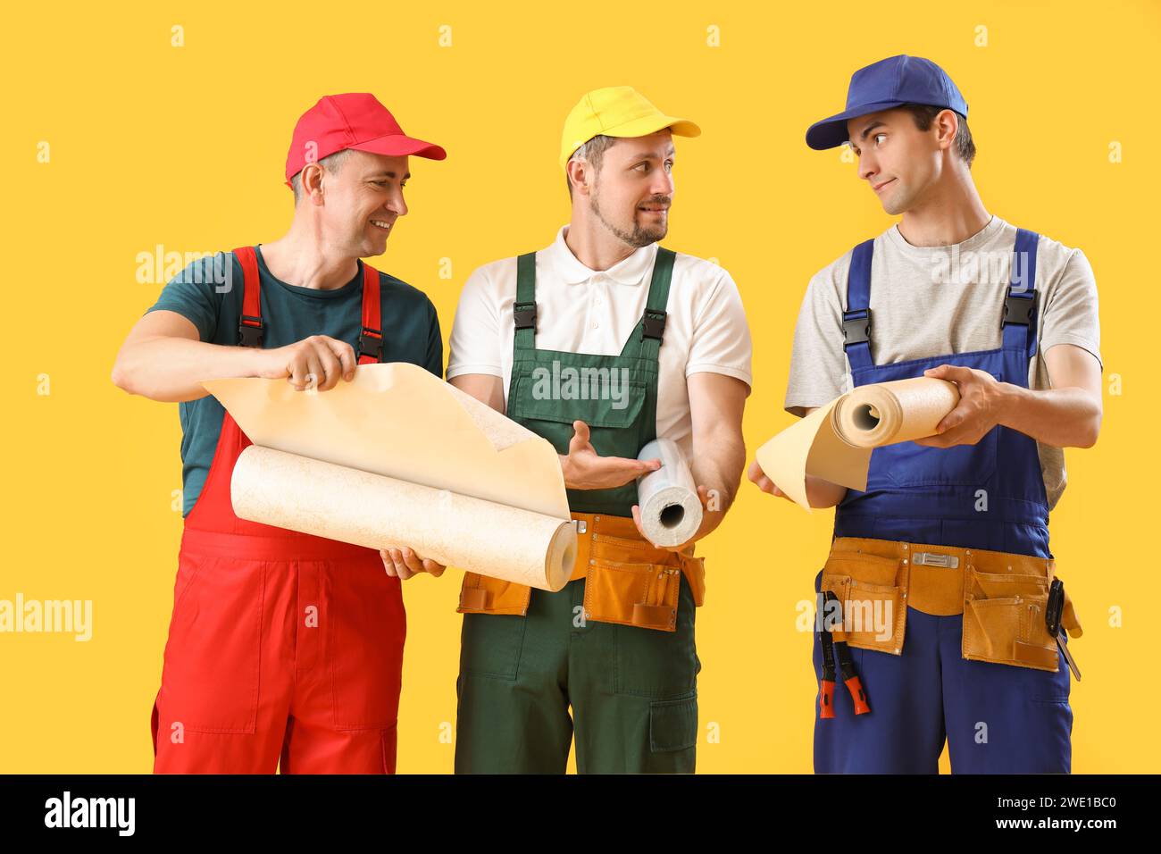 Team of male builders with wallpapers on yellow background Stock Photo ...