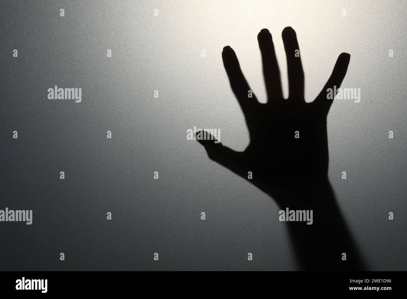 Silhouette of creepy ghost behind glass against grey background ...