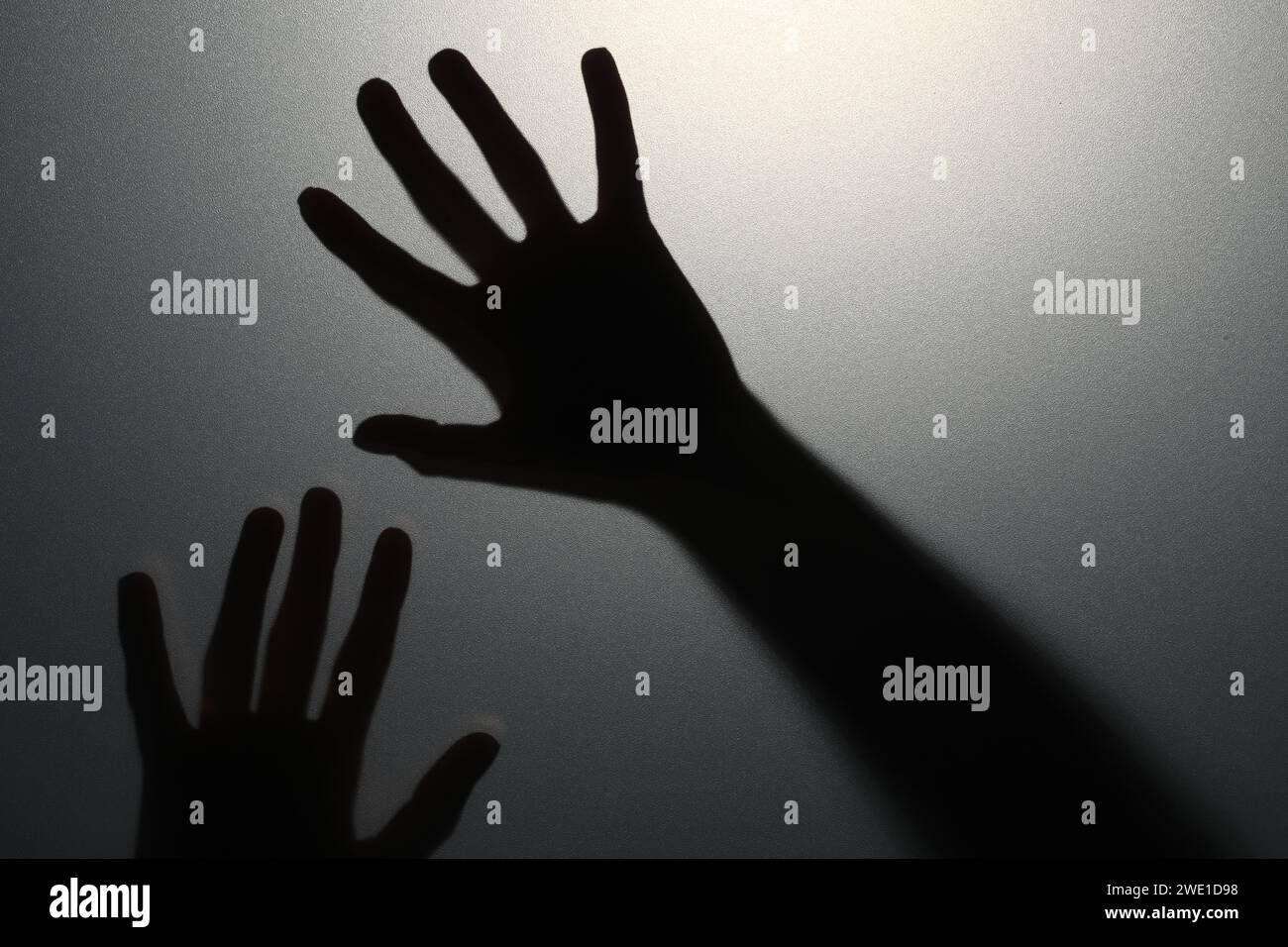 Silhouette of creepy ghost behind glass against grey background ...