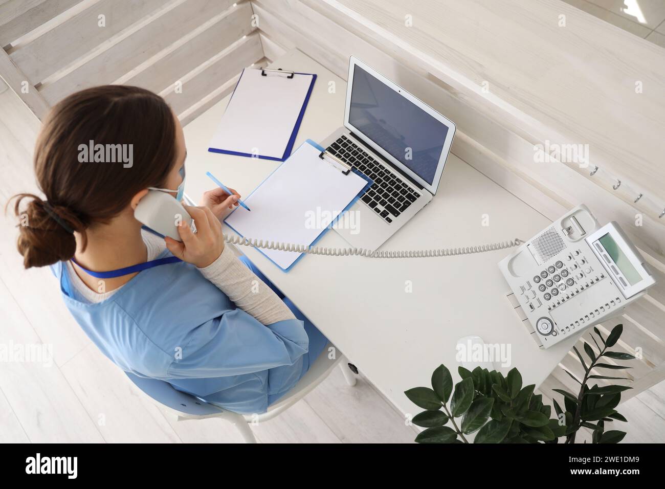 Female medical intern talking by telephone at reception in clinic Stock ...