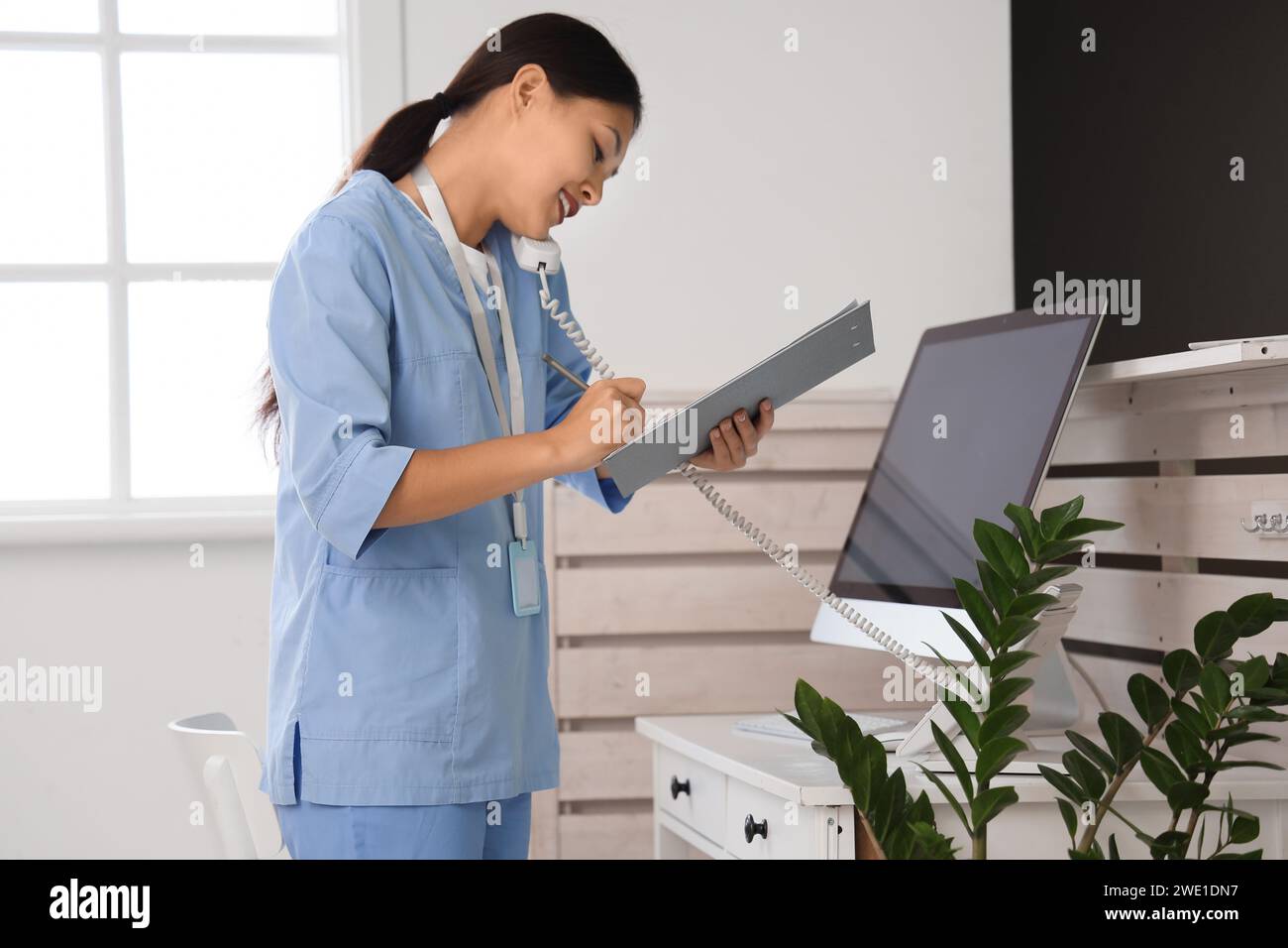 Female Asian medical intern talking by telephone in clinic Stock Photo ...