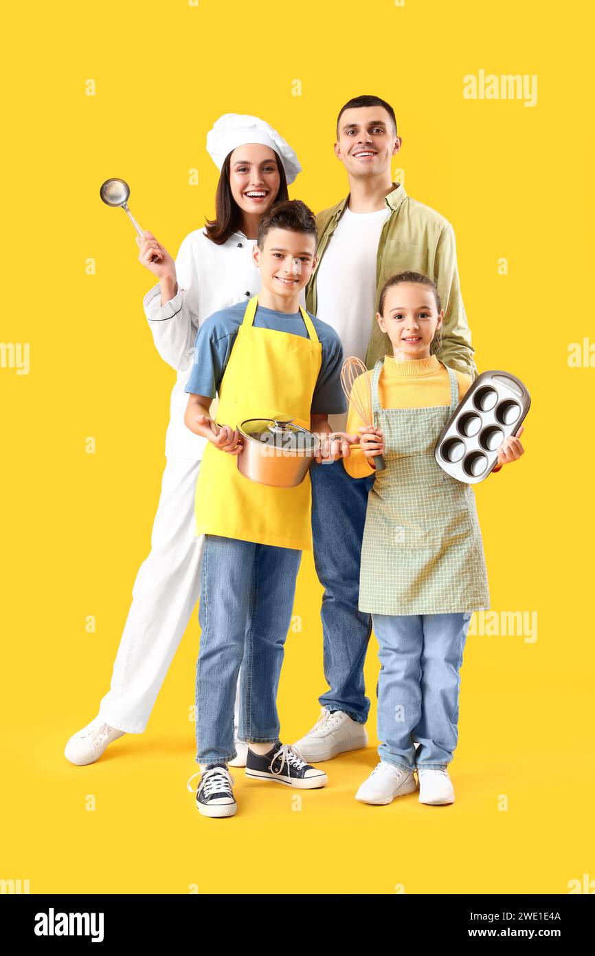 Happy family with kitchen utensils on yellow background Stock Photo - Alamy