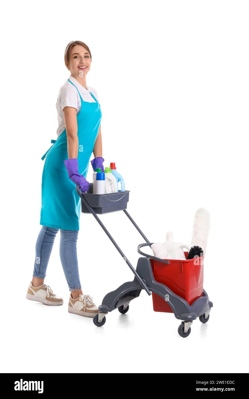 Female janitor with trolley of cleaning supplies on white background ...