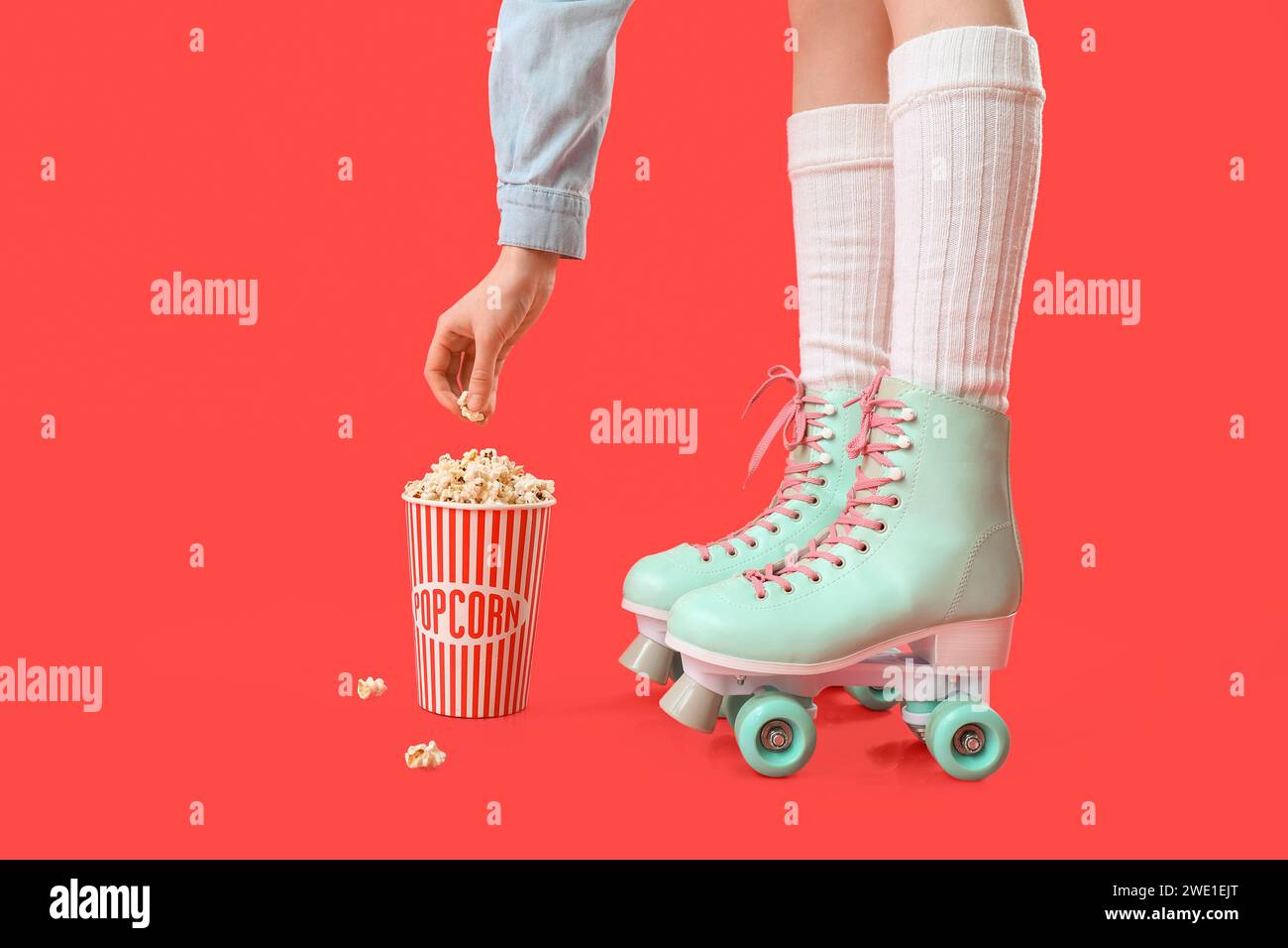 Bucket of popcorn and legs of woman in roller skates on red background ...