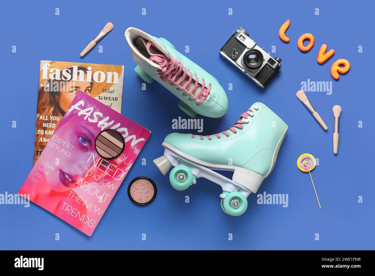 Composition with pair of vintage roller skates, photo camera, magazines ...