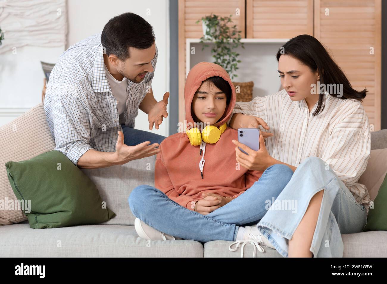 Teenage boy and his parents with mobile phone at home. Family problem ...