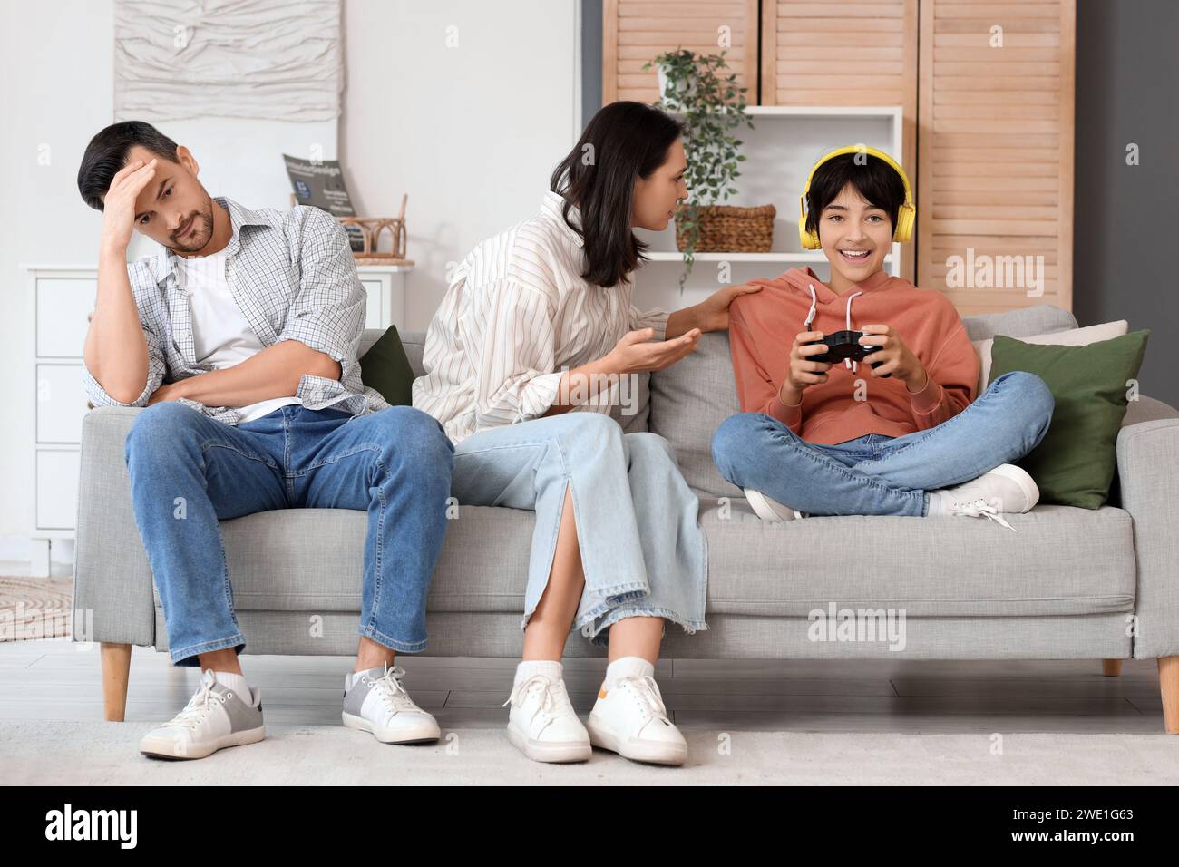 Teenage boy playing video game and his upset parents at home. Family ...