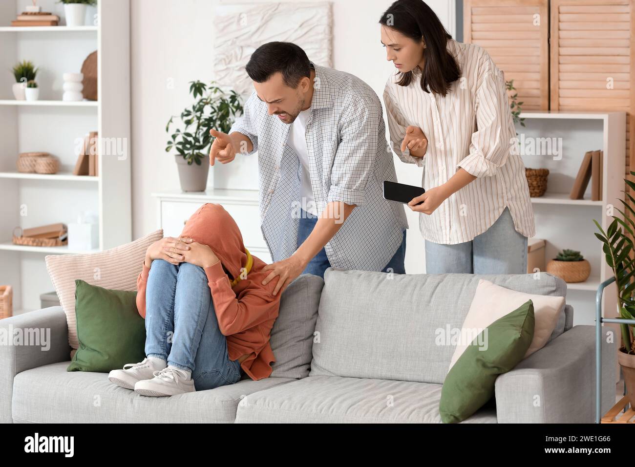Teenage boy sitting on sofa and his arguing parents at home. Family ...