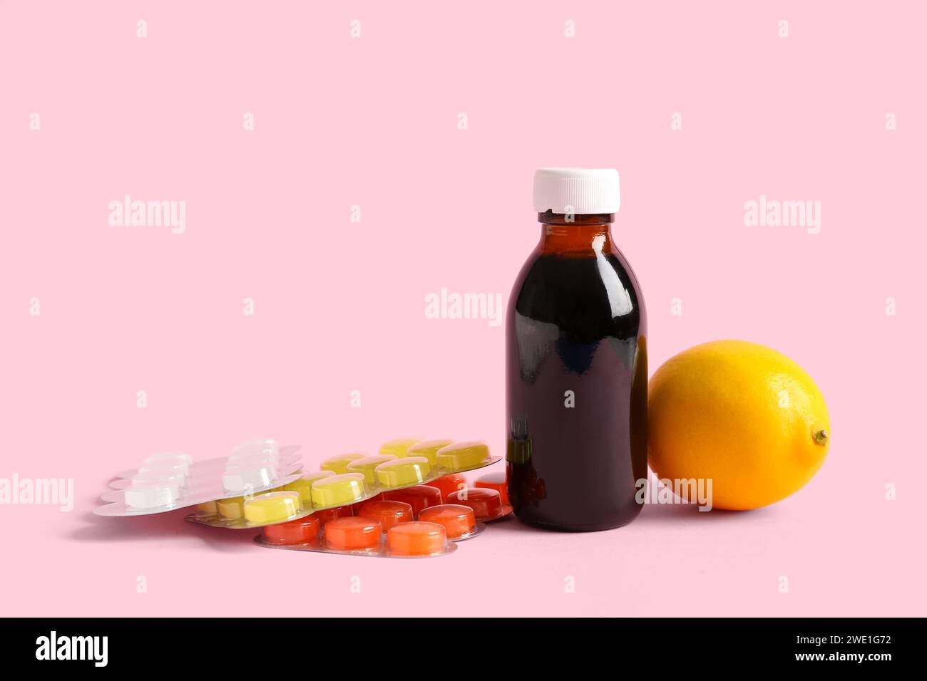 Pills for sore throat with cough syrup and lemon on pink background ...