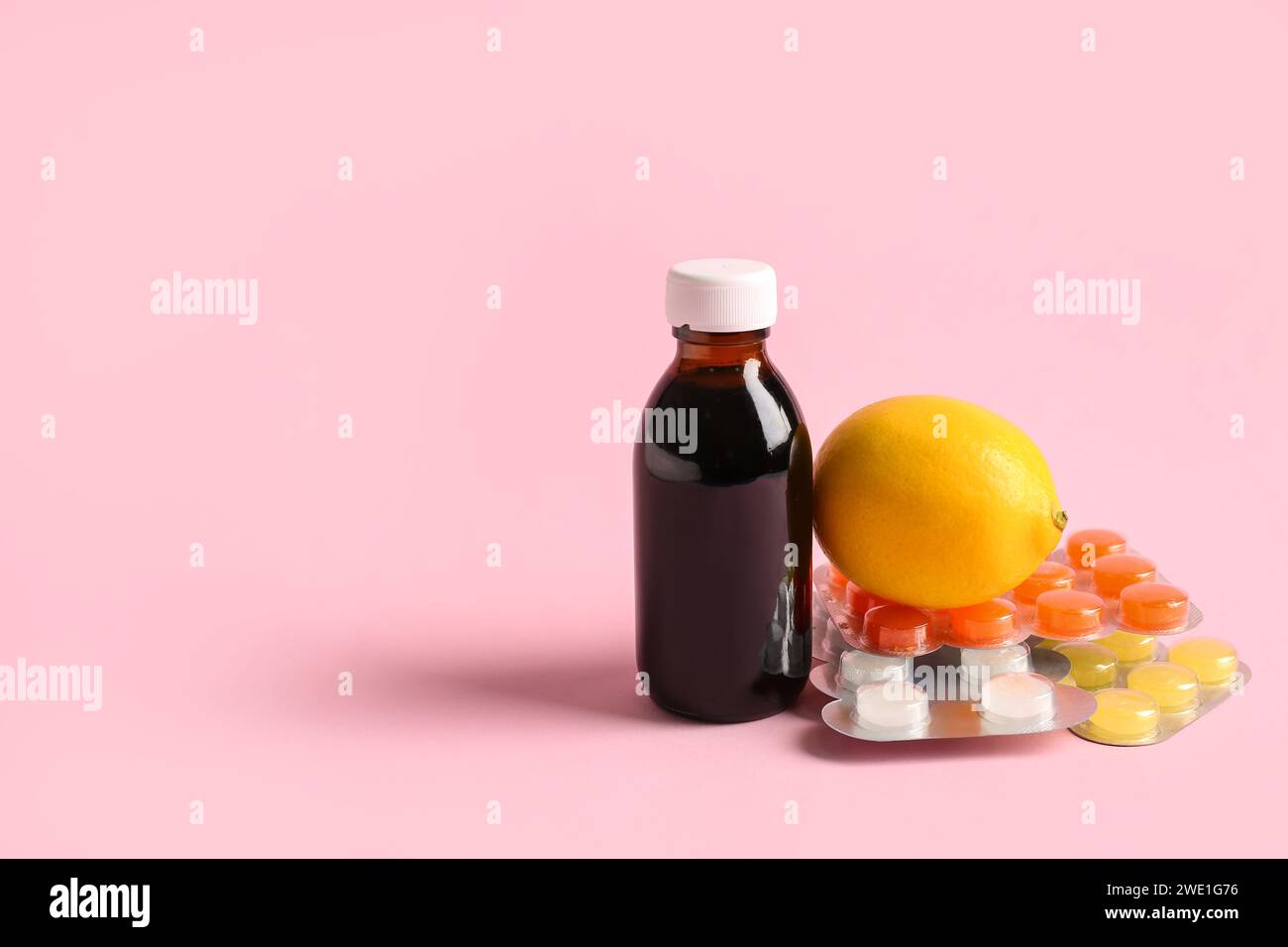 Pills for sore throat with cough syrup and lemon on pink background ...
