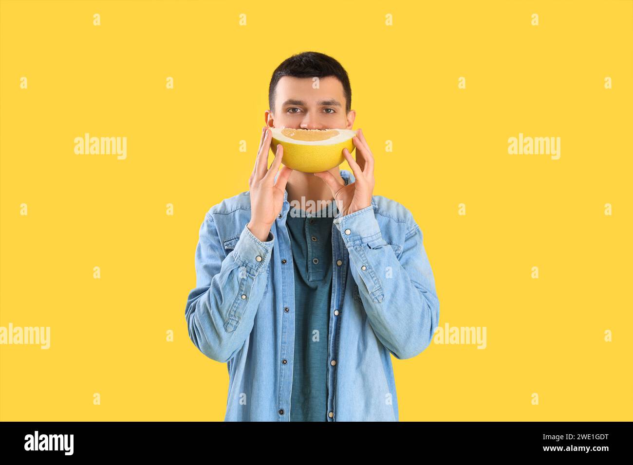 Young man eating pomelo on yellow background Stock Photo - Alamy