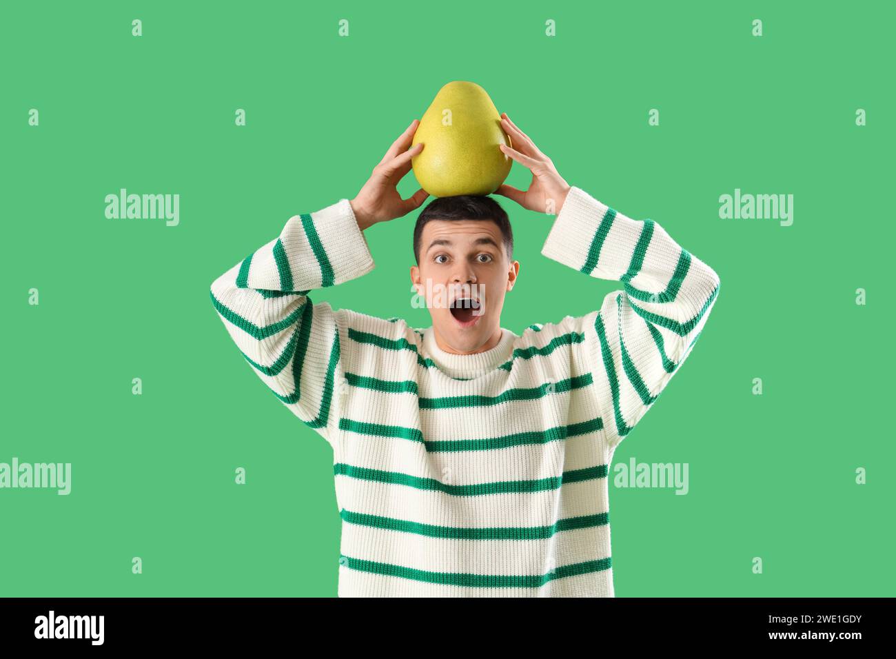 Shocked young man with pomelo on green background Stock Photo - Alamy