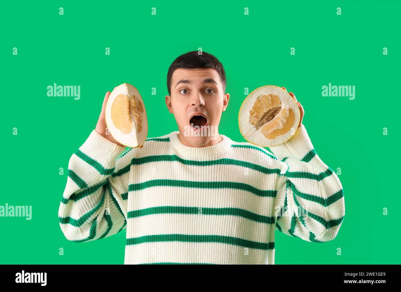 Shocked young man with cut pomelo on green background Stock Photo - Alamy