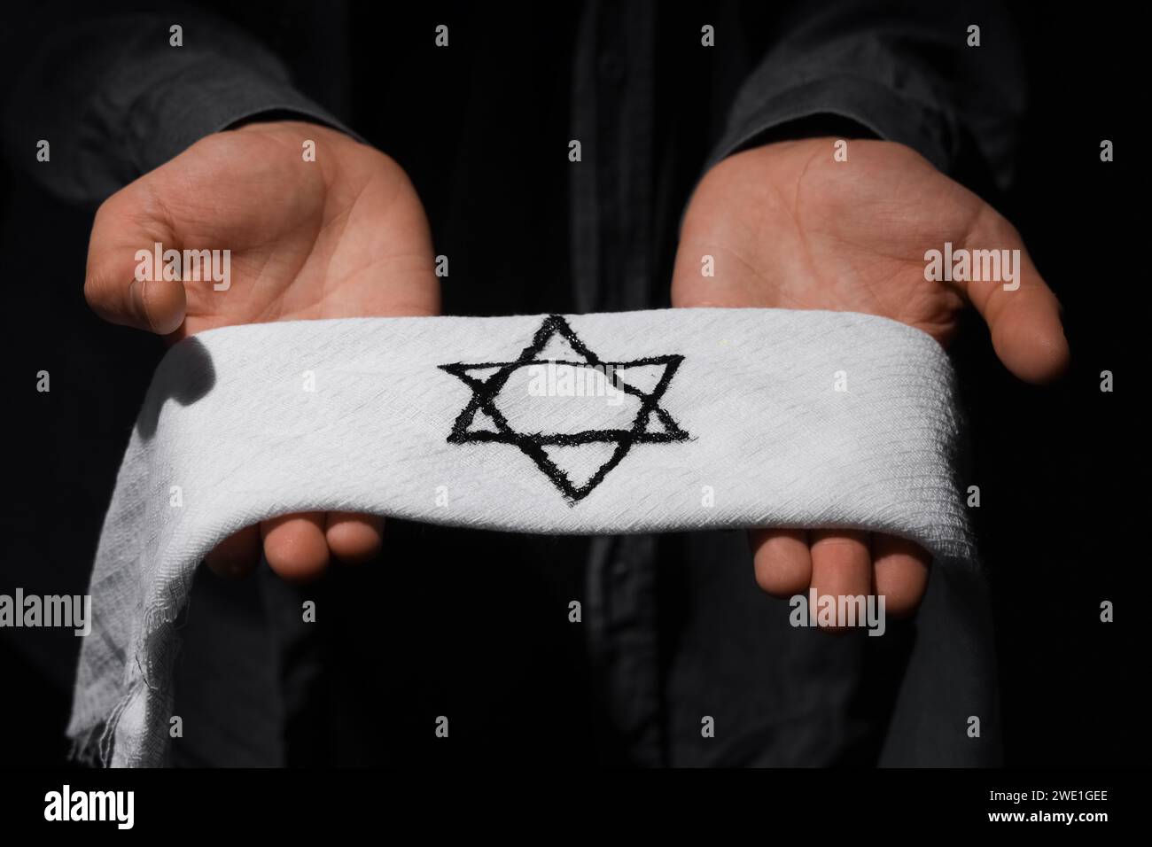 Young Jewish man with armband on black background, closeup ...