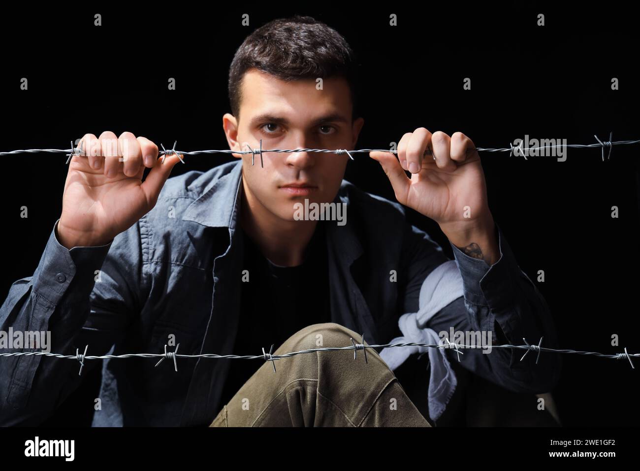 Young Jewish man behind barbed wire on black background. International ...