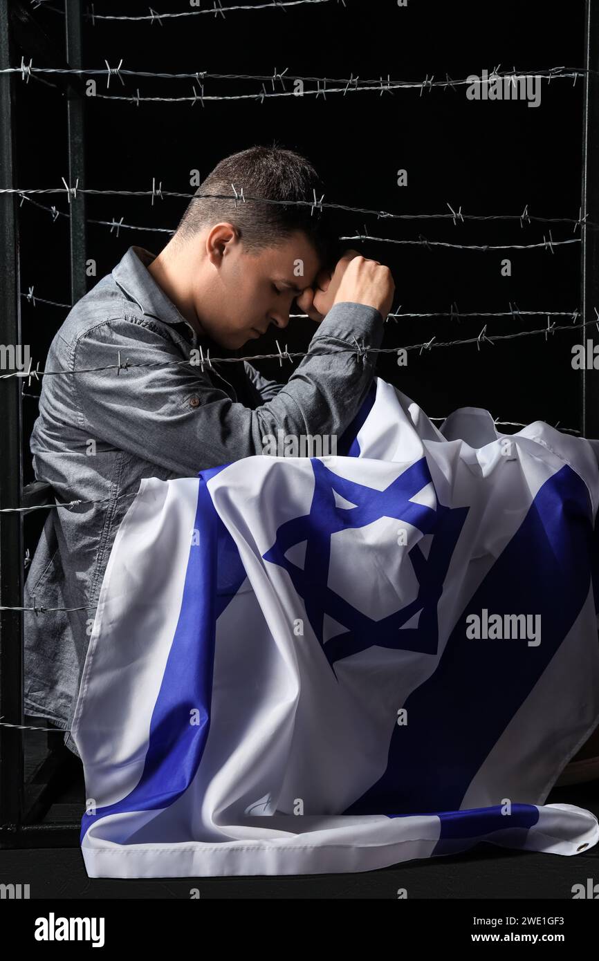 Young Jewish man with flag of Israel praying behind barbed wire on ...